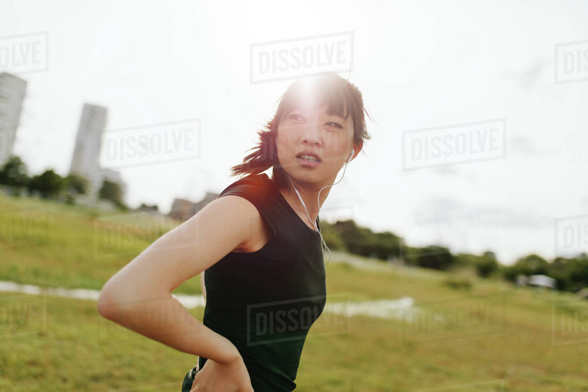 Shot of confident young woman looking back while standing outdoors ...