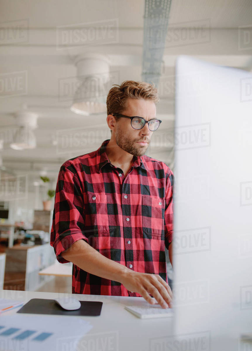 Vertical shot of young man working on computer. Businessman ...
