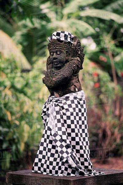 Statue of a warrior wearing a checkered skirt in the forest, Bali ...