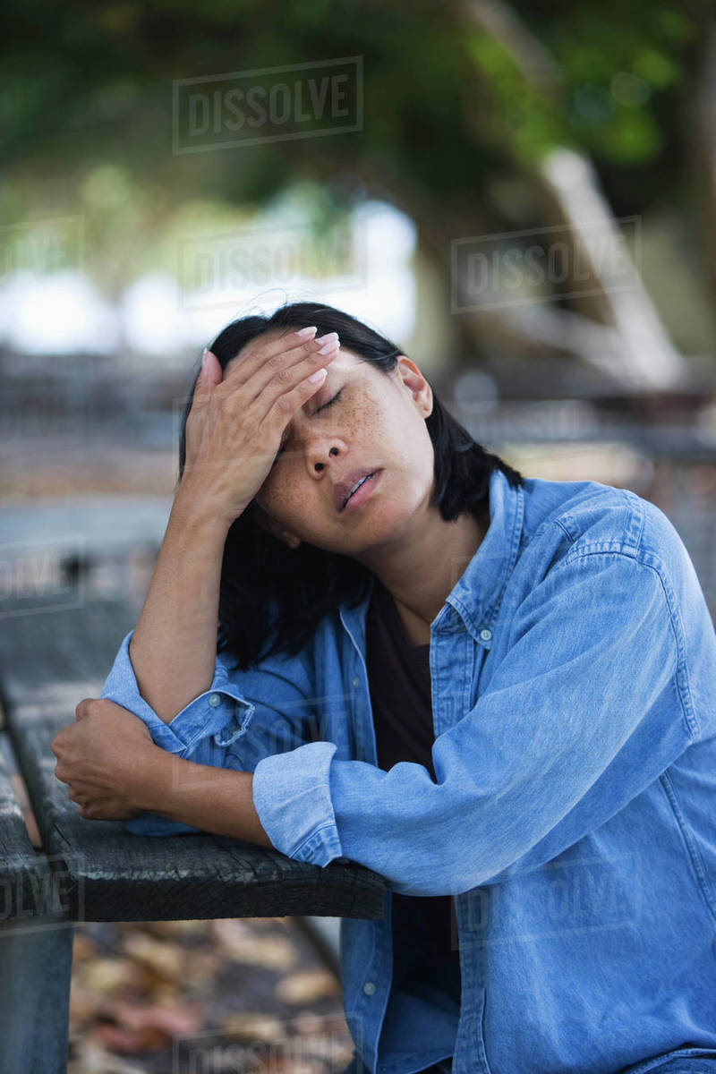 Worried Filipino woman sitting at picnic table - Royalty-free Stock ...