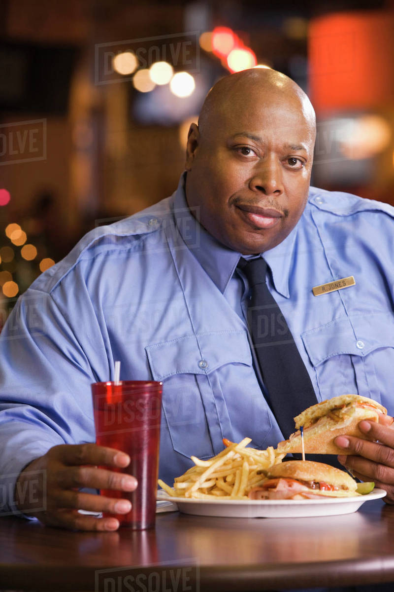 Black police officer eating unhealthy food - Royalty-free Stock Photo ...