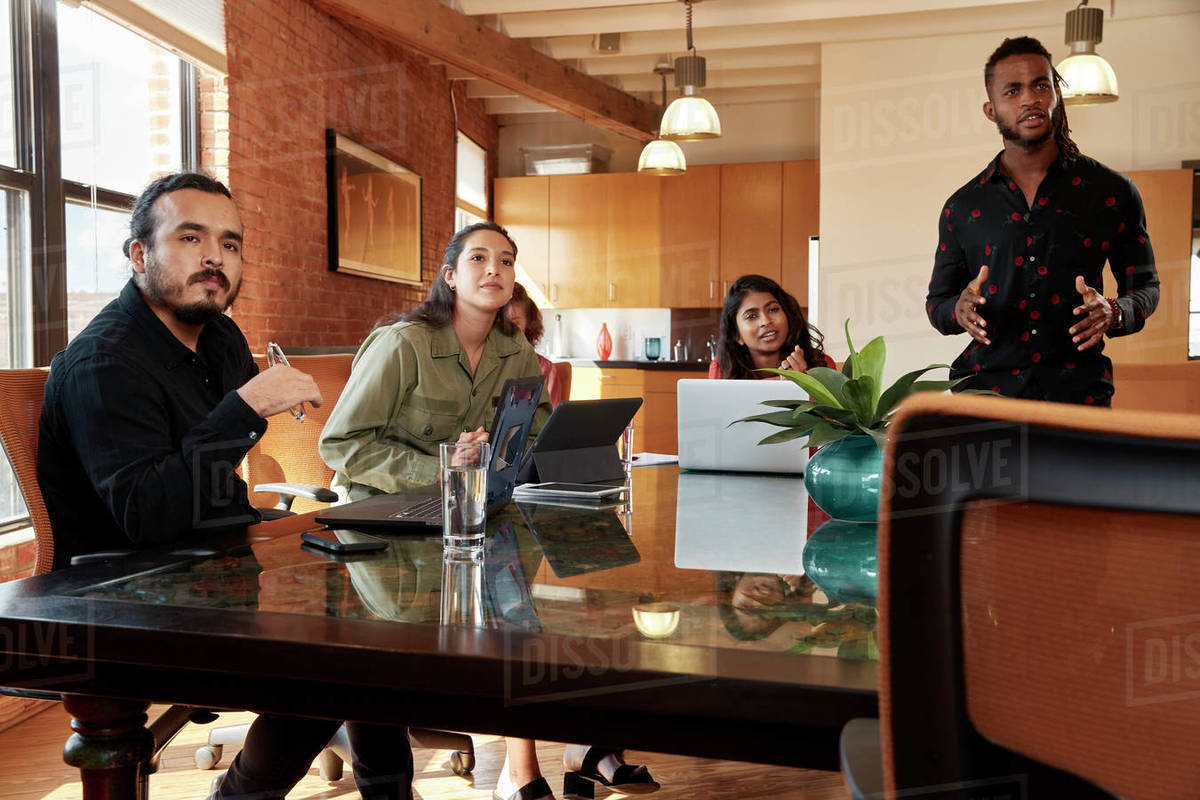 Group of co-workers sitting at large conference table with their ...
