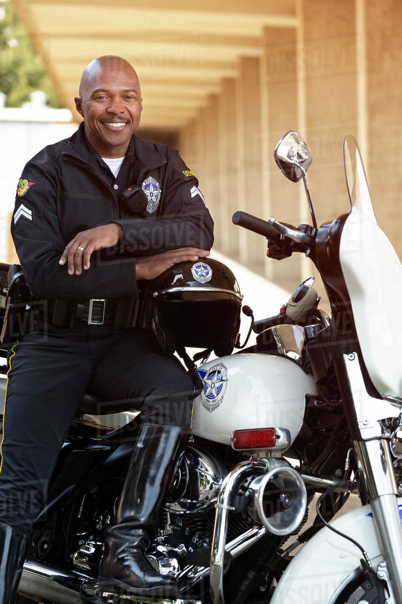 Portrait of Police officer sitting on his motorcycle outside looking ...