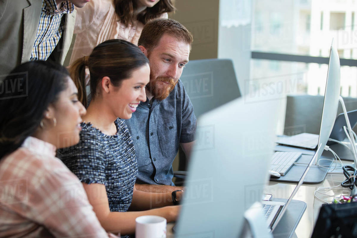 Young woman using laptop computer in conference room showing co-workers ...
