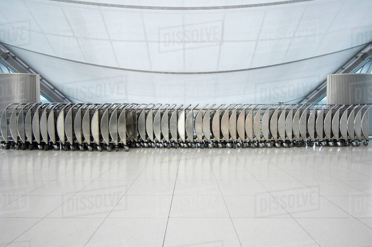 Neatly stacked row of stainless steel airport baggage carts placed ...