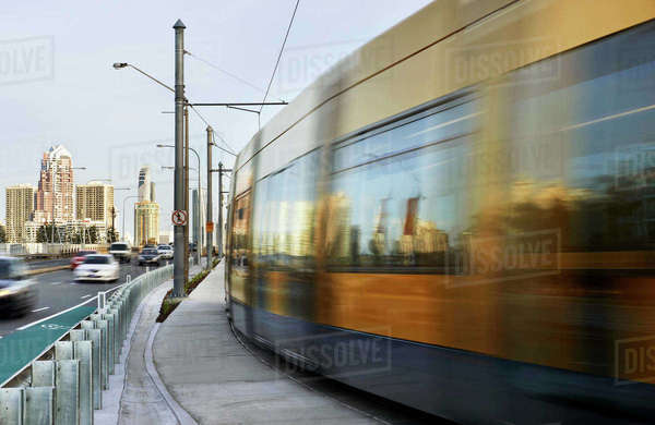 Tram travelling alongside road and Surfers Paradise city in the ...