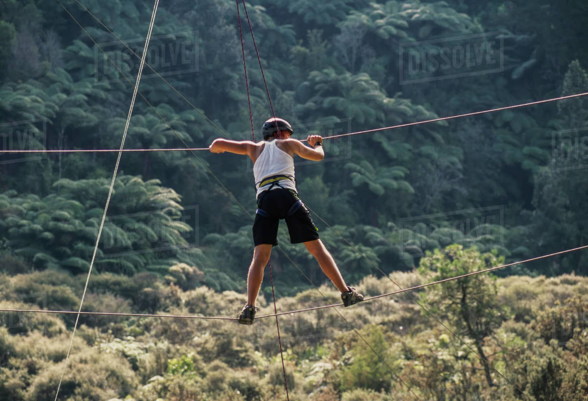 Man manoeuvring along suspended ropes on outdoor ropes course - Stock ...