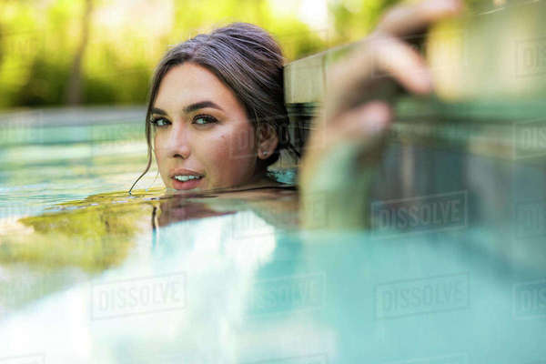 Portrait of caucasian woman floating in swimming pool in backyard ...