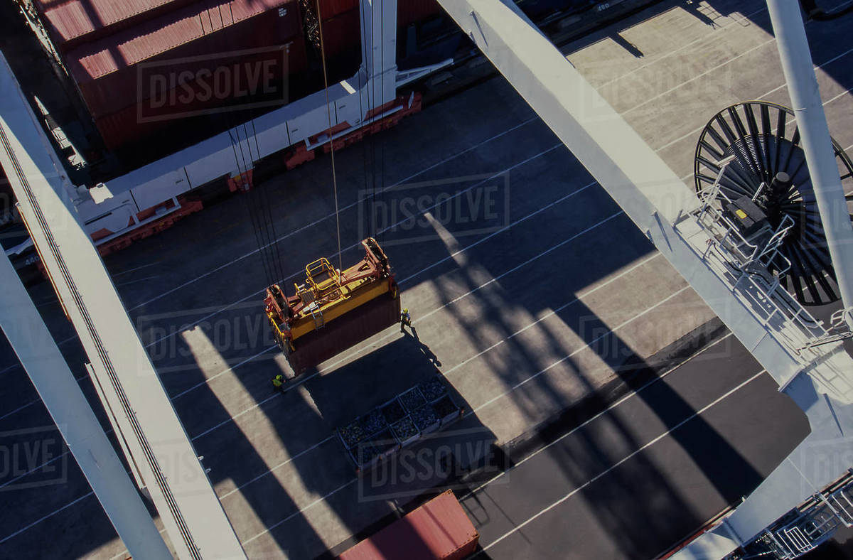 Looking down from crane at shipping container being secured for loading ...