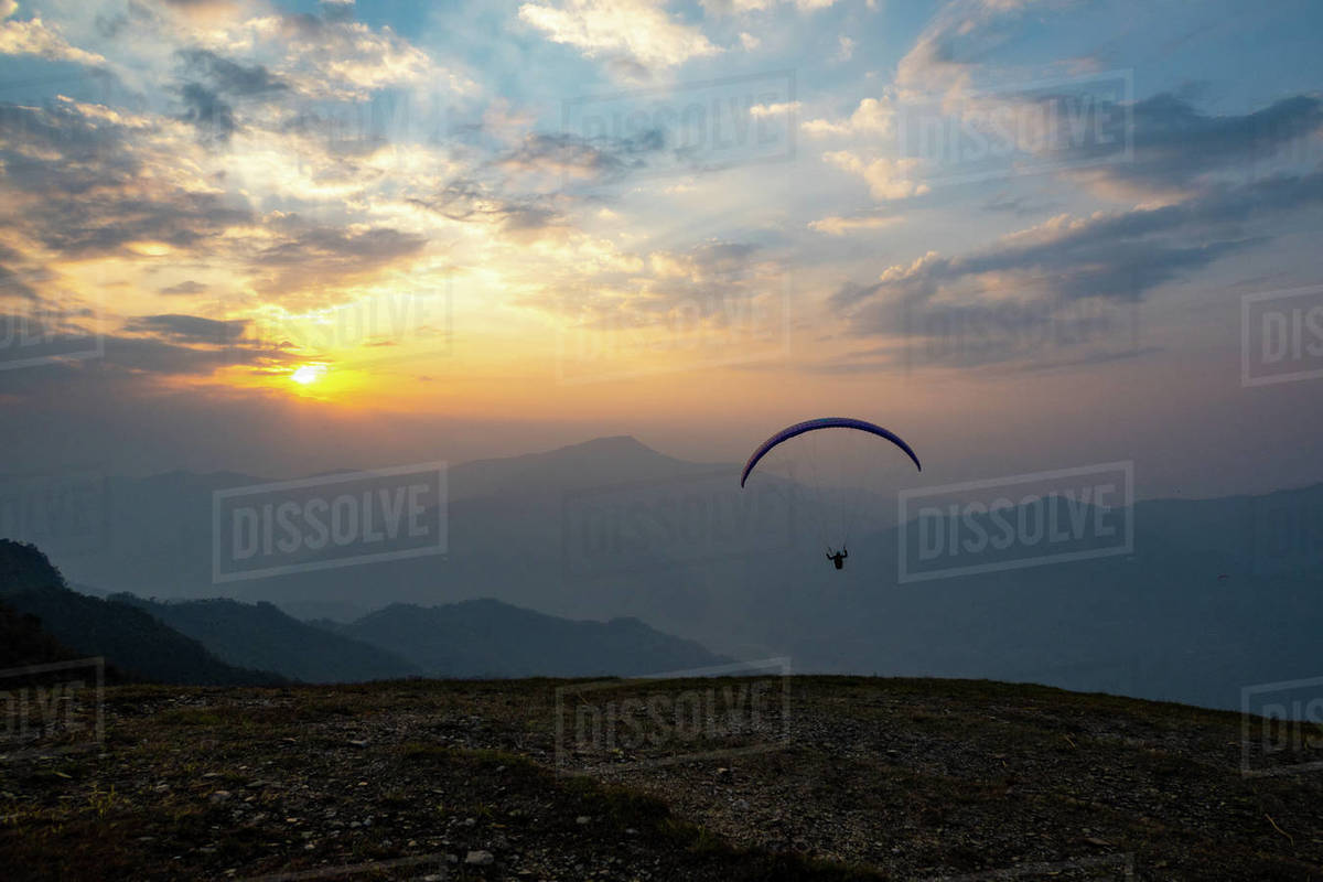 Paraglider taking off from cliff at sunset in Nepal. - Royalty-free ...