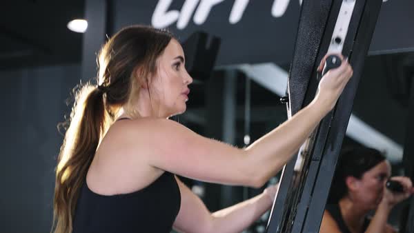 Fit woman builds strength from a vertical climbing exercise in a group ...