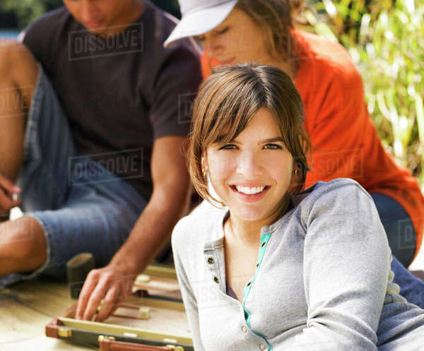 Young adults relaxing outside and a couple playing backgammon sitting ...