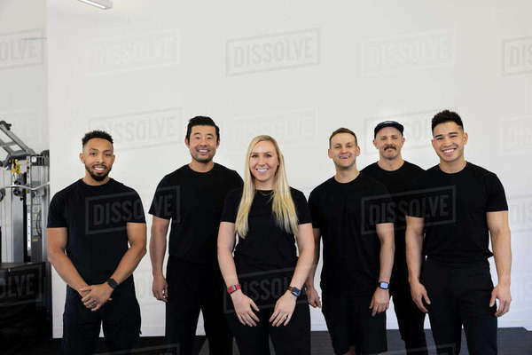 Smiling group of six fitness trainers looking into camera with a ...