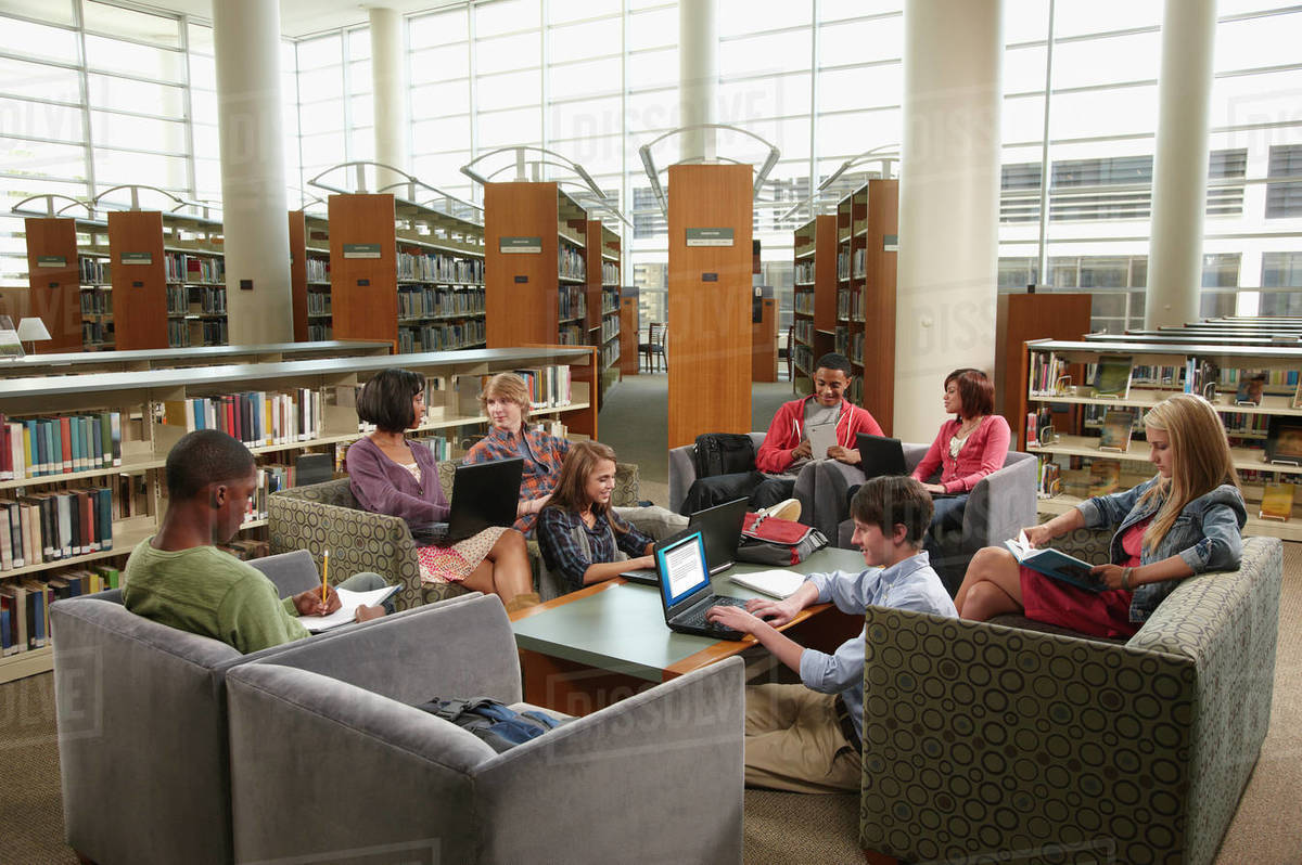 Group of young college students working together on project in library ...
