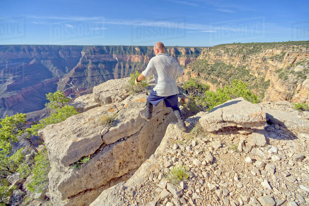 A man jumping across a cliff crevice east of Shoshone Point at Grand ...