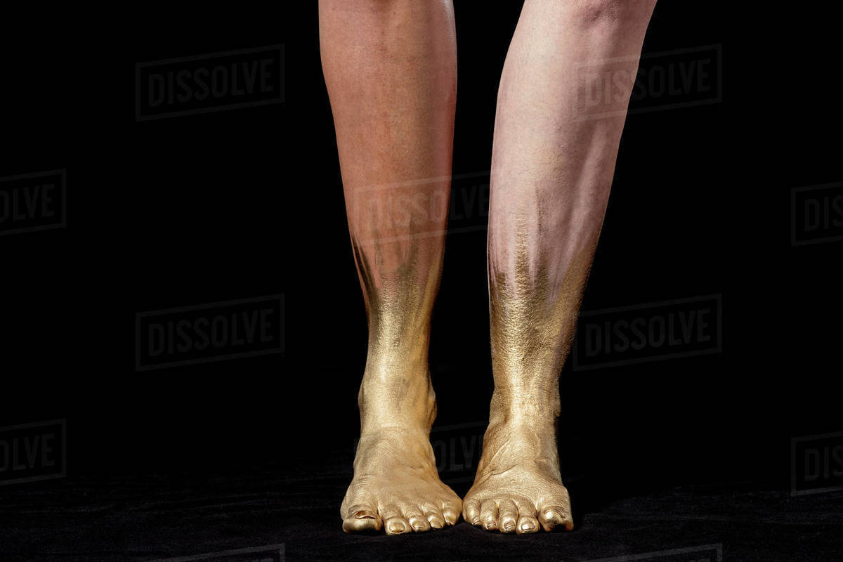 Close-up shot of mixed race and Caucasian women's legs and gold painted ...