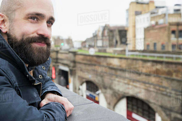 Man looking over ledge of building from rooftop patio - Stock Photo ...