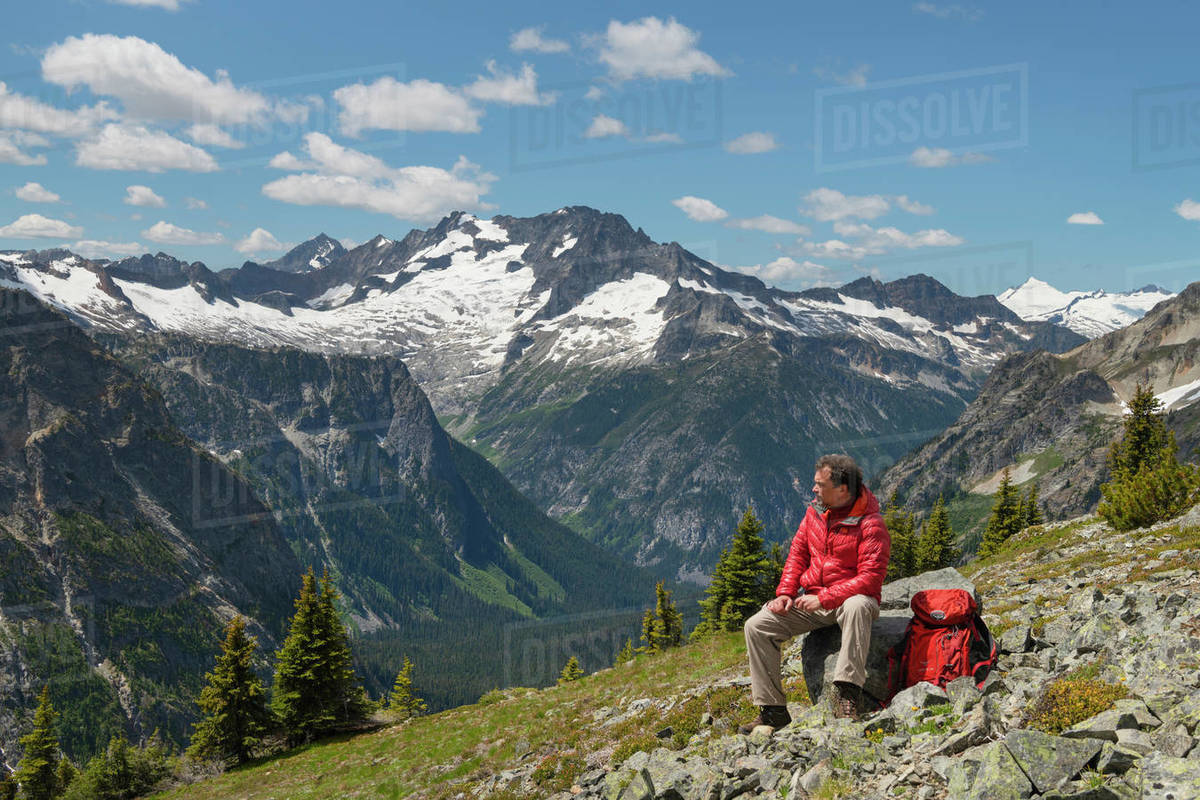 Adult male hiker with red jacket and backpack relaxing on Ragged Ridge ...