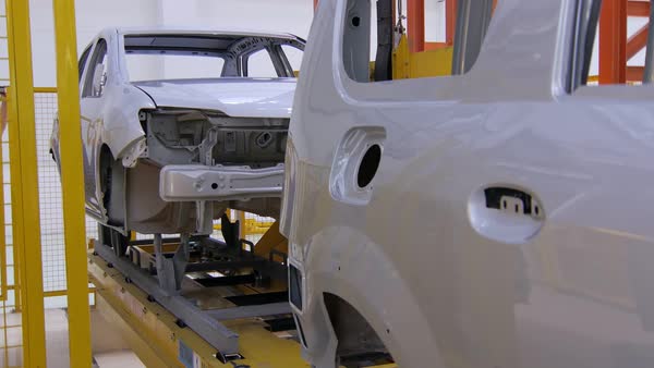 Transporting belt is moving car bodies inside a workshop, putting one ...