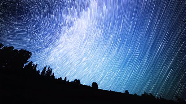 Rotating night sky with stars and Milky Way galaxy over mountains and ...