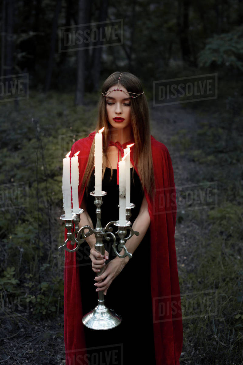 Beautiful mystic girl in red cloak holding candelabrum with flaming ...