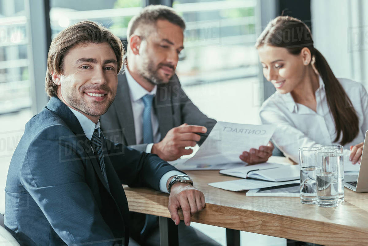 Handsome businessman looking at camera during meeting at modern office ...