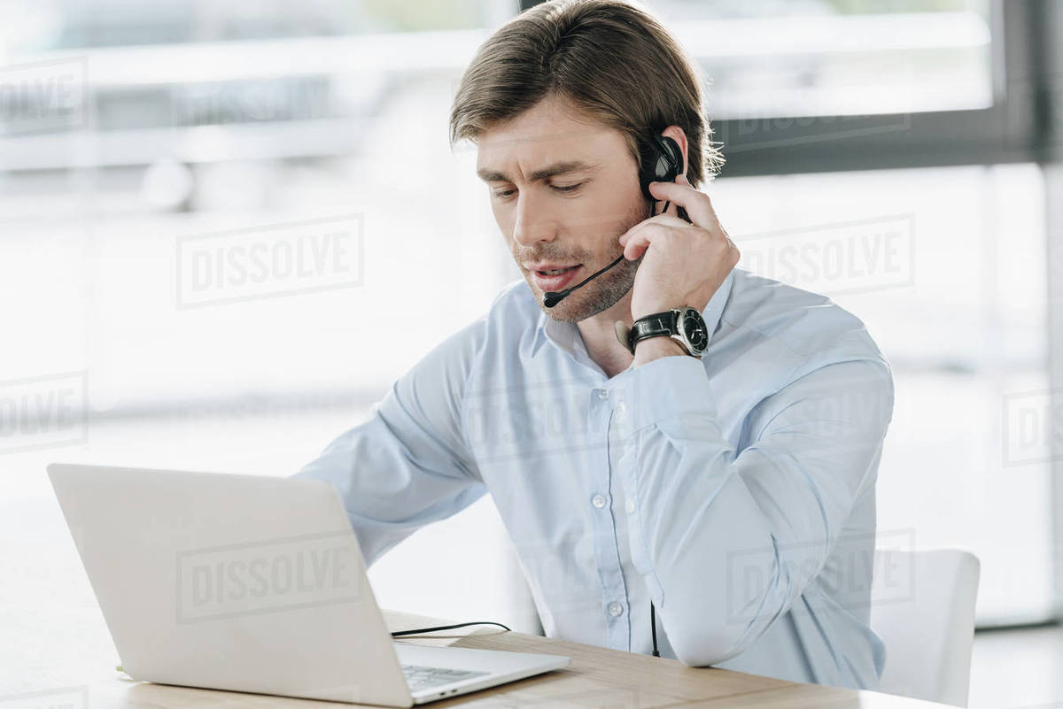 Confident call center worker with laptop sitting at workplace - Royalty ...