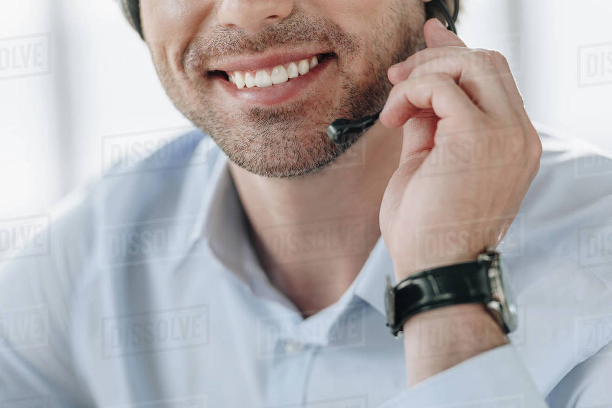 Cropped shot of smiling support hotline worker holding microphone ...