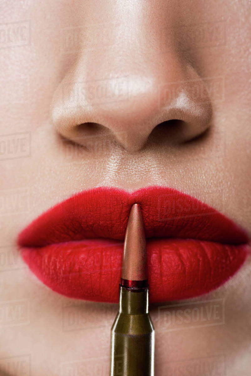 Cropped view of girl holding bullet near red lips, isolated on grey ...