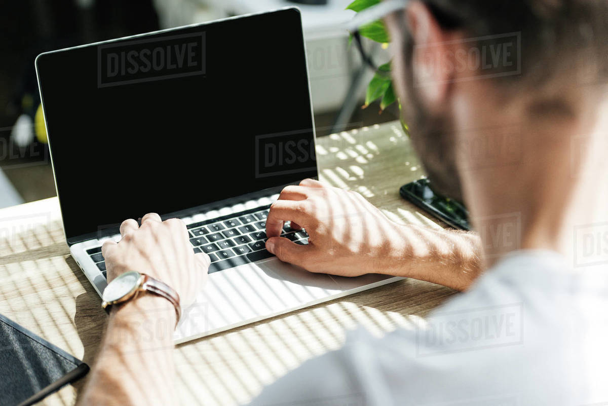 Back view of man using laptop with blank screen on workplace - Stock ...
