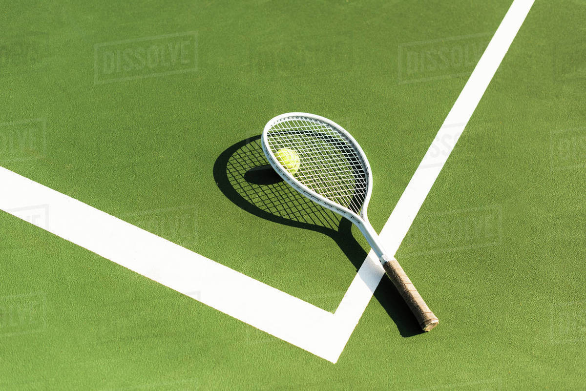 close up view of tennis racket and ball lying on green tennis court ...