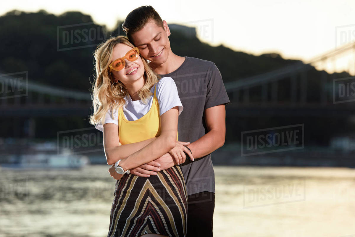 happy boyfriend hugging girlfriend on river beach in evening - Royalty ...