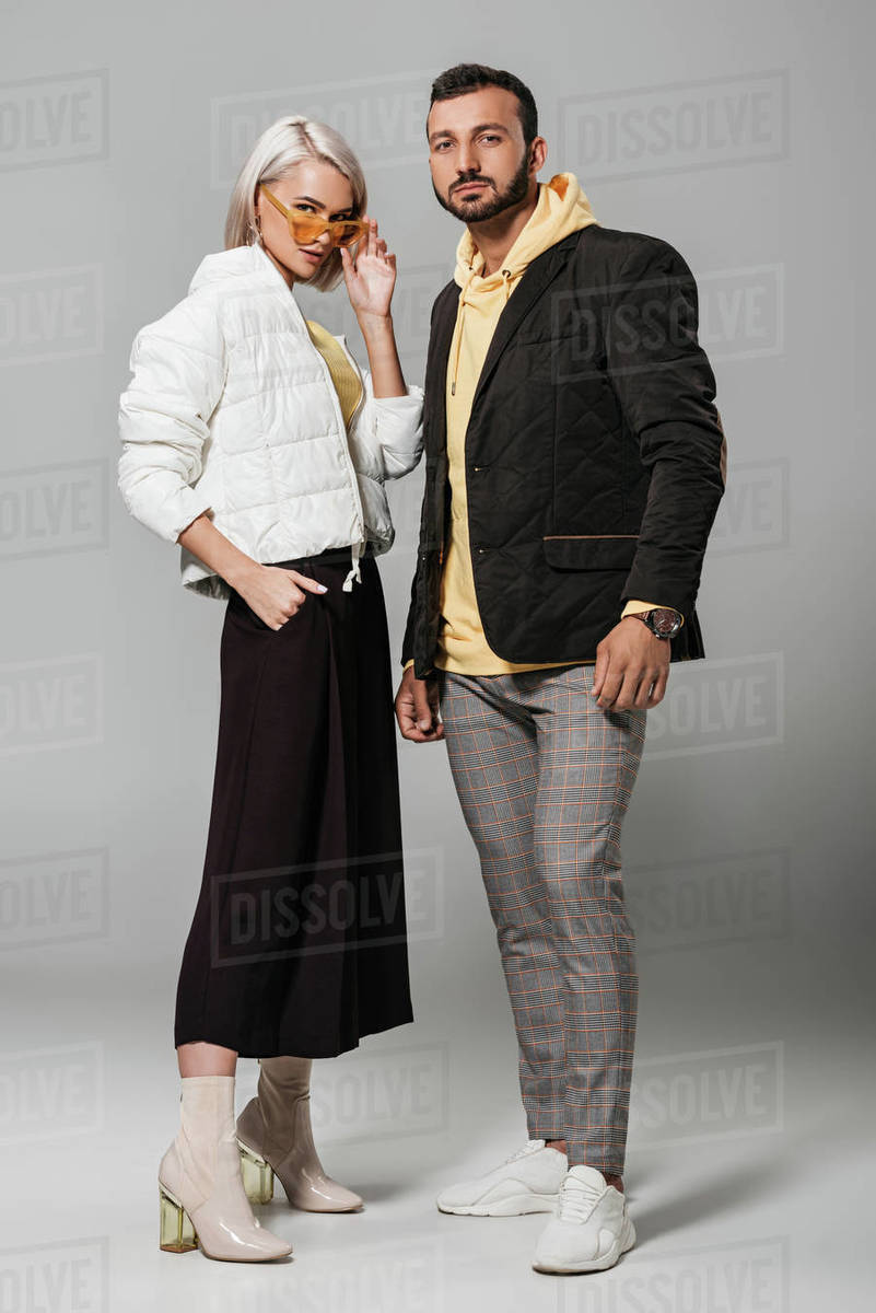 fashionable couple of models in autumn outfits posing on grey ...
