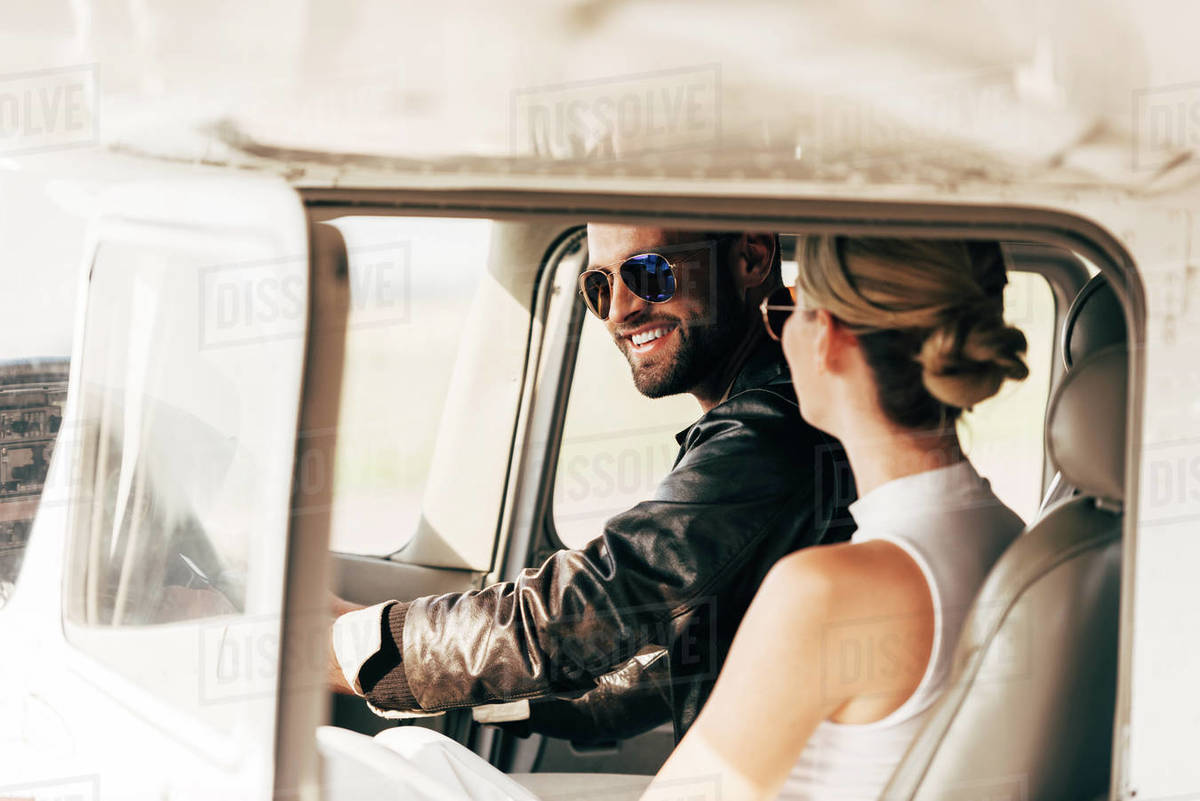 Smiling male pilot in sunglasses and leather jacket with his girlfriend ...