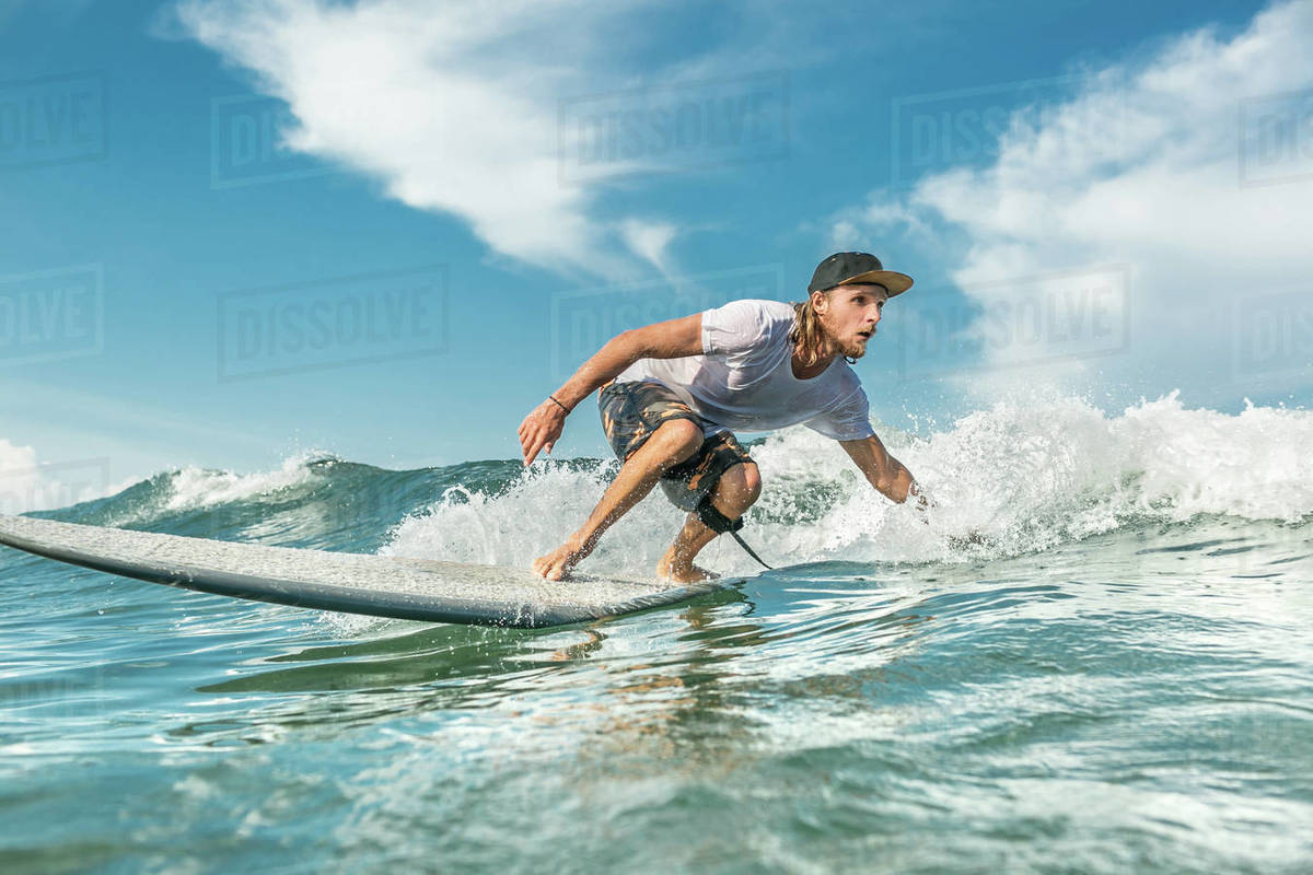 Concentrated male surfer riding waves in ocean at Nusa Dua Beach, Bali ...