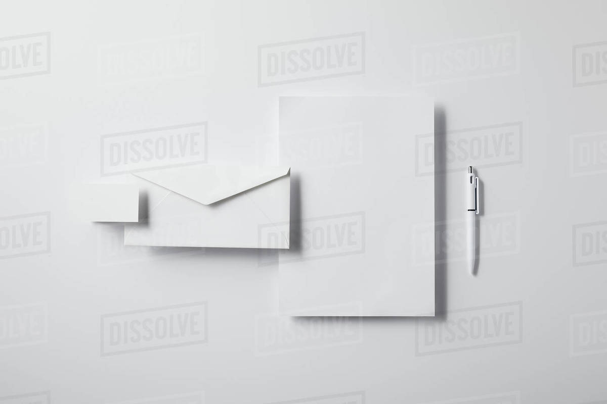 Top view of layered envelope with pen, blank paper and business card on ...