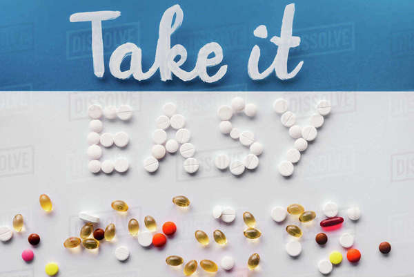 top view of lettering take it easy made by pills near various tablets ...