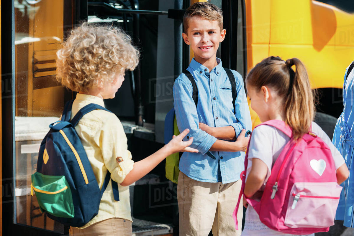 adorable pupils chatting near school bus - Royalty-free Stock Photo ...