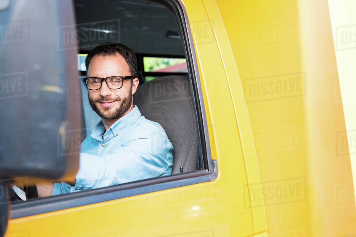 handsome happy school bus driver looking at camera - Stock Photo - Dissolve