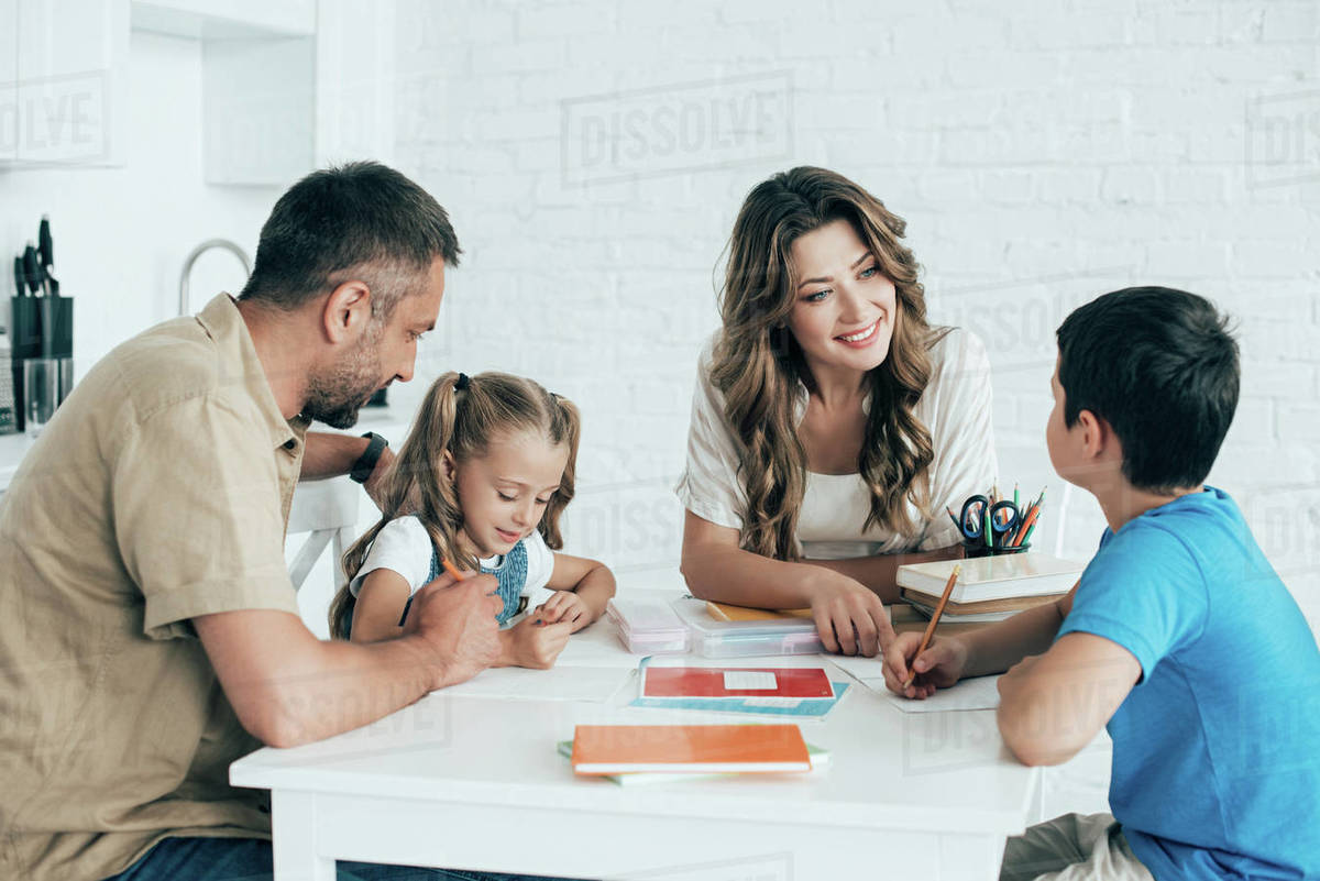 parents helping children with homework at table at home - Royalty-free ...
