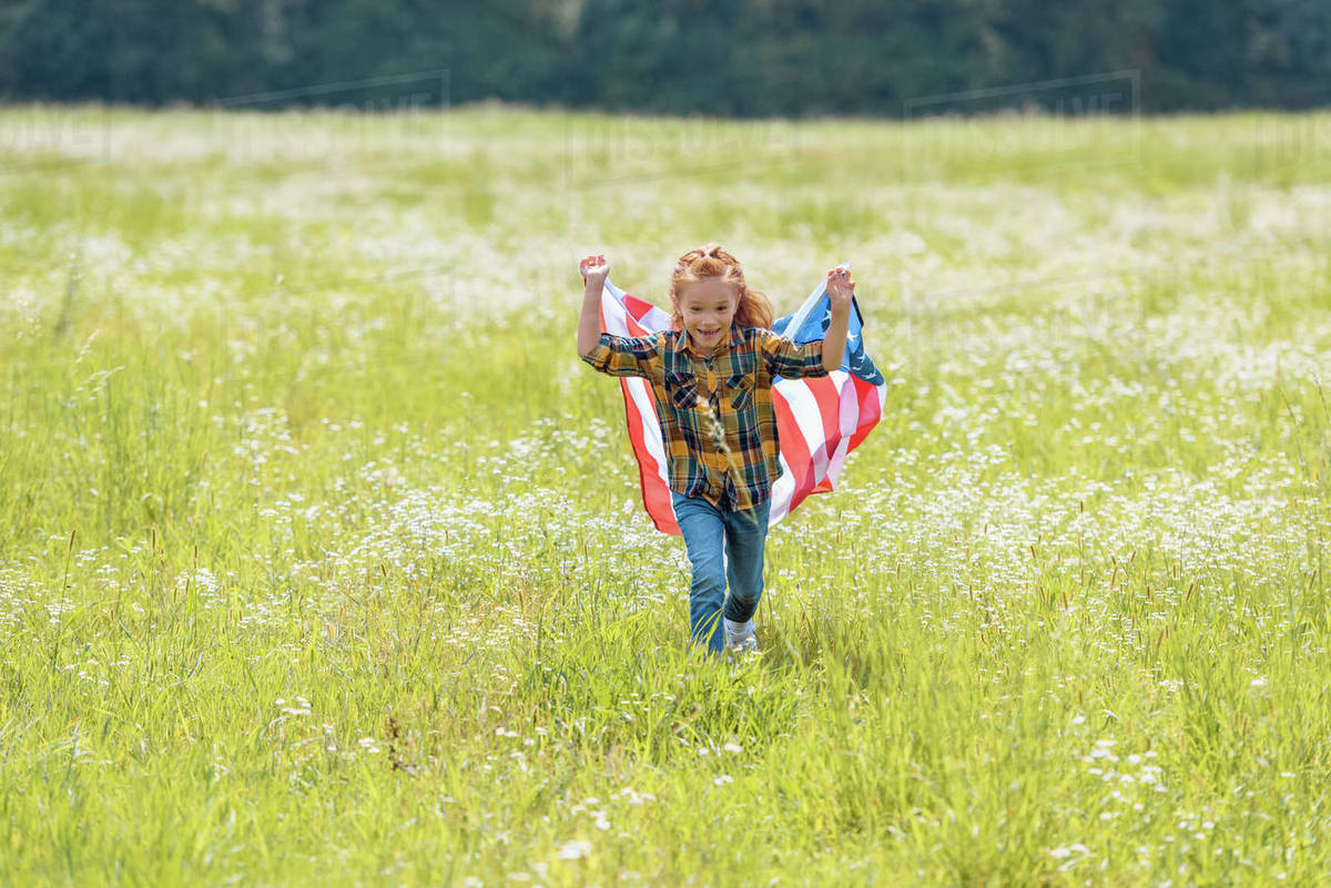 cheerful child running in field with american flag in hands - Royalty ...
