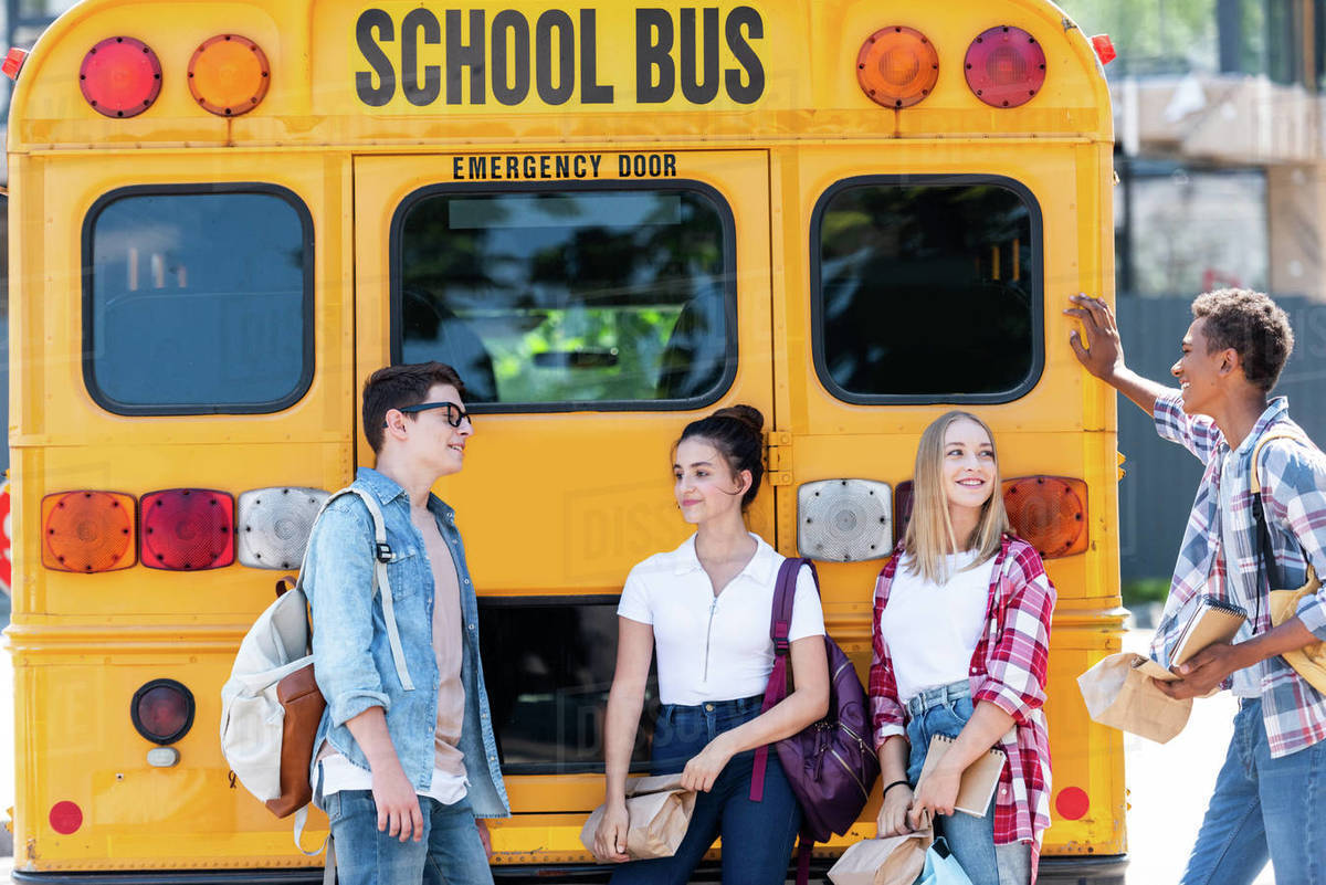 group of teen scholars chatting while leaning on school bus - Royalty ...