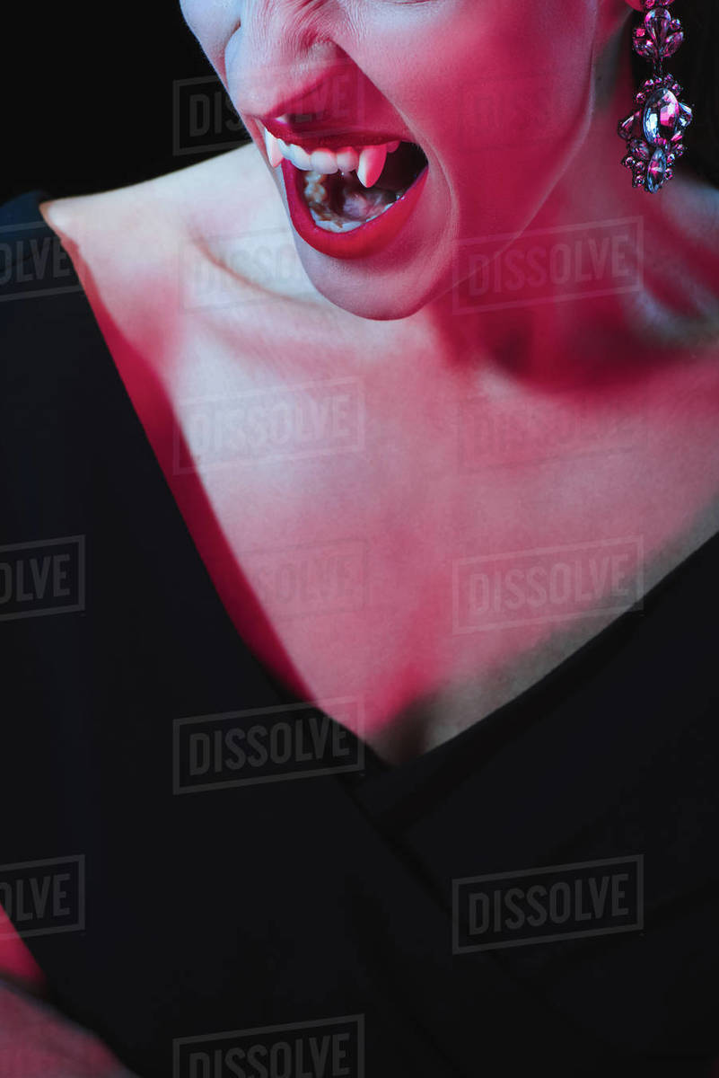 Cropped view of vampire showing her fangs on dark background - Stock ...