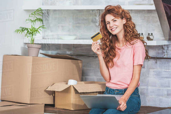 Beautiful happy young woman holding credit card and smiling at camera ...