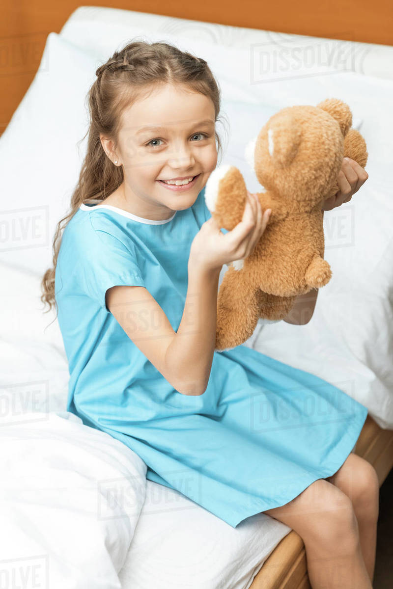 Little patient with teddy bear sitting on bed in hospital - Stock Photo ...