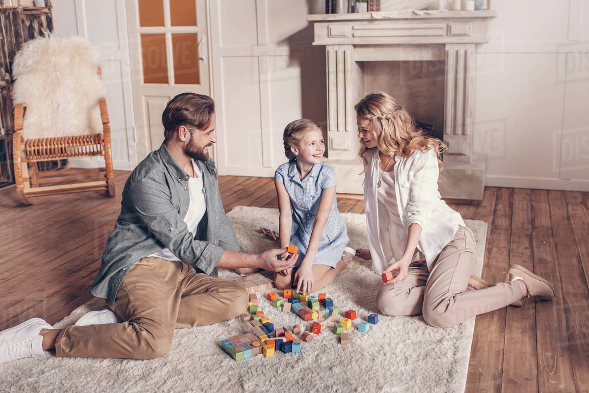 Happy family playing with constructor and sitting on floor at home ...