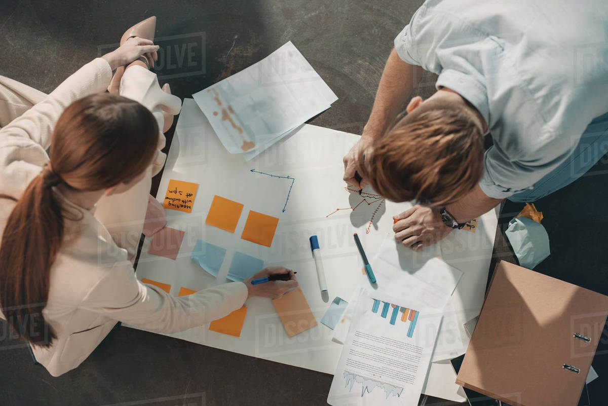 Overhead view of young business people sitting on floor and working ...