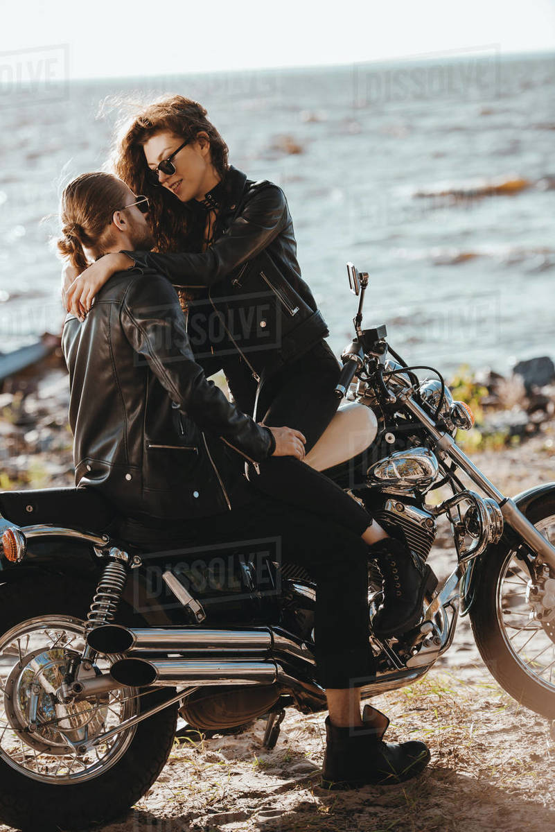 Couple of bikers hugging on classical motorcycle on seashore - Royalty ...