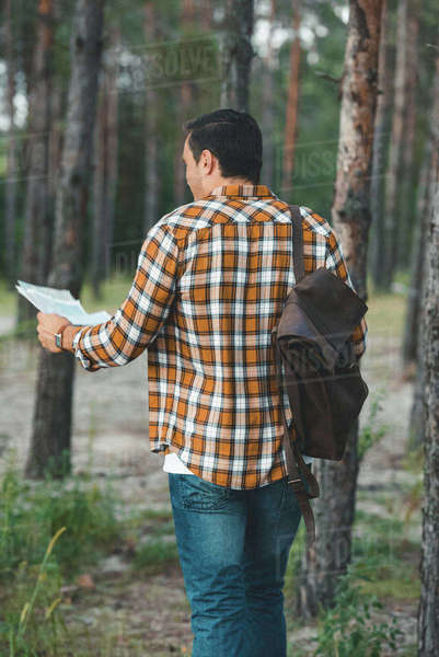 Back view of tourist with map and backpack in forest - Royalty-free ...