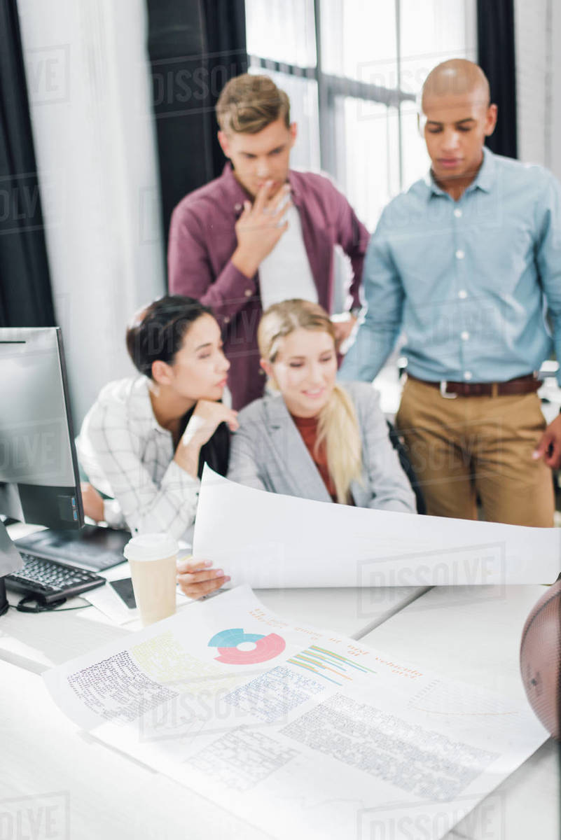 Focused young multiethnic coworkers working with business charts in ...